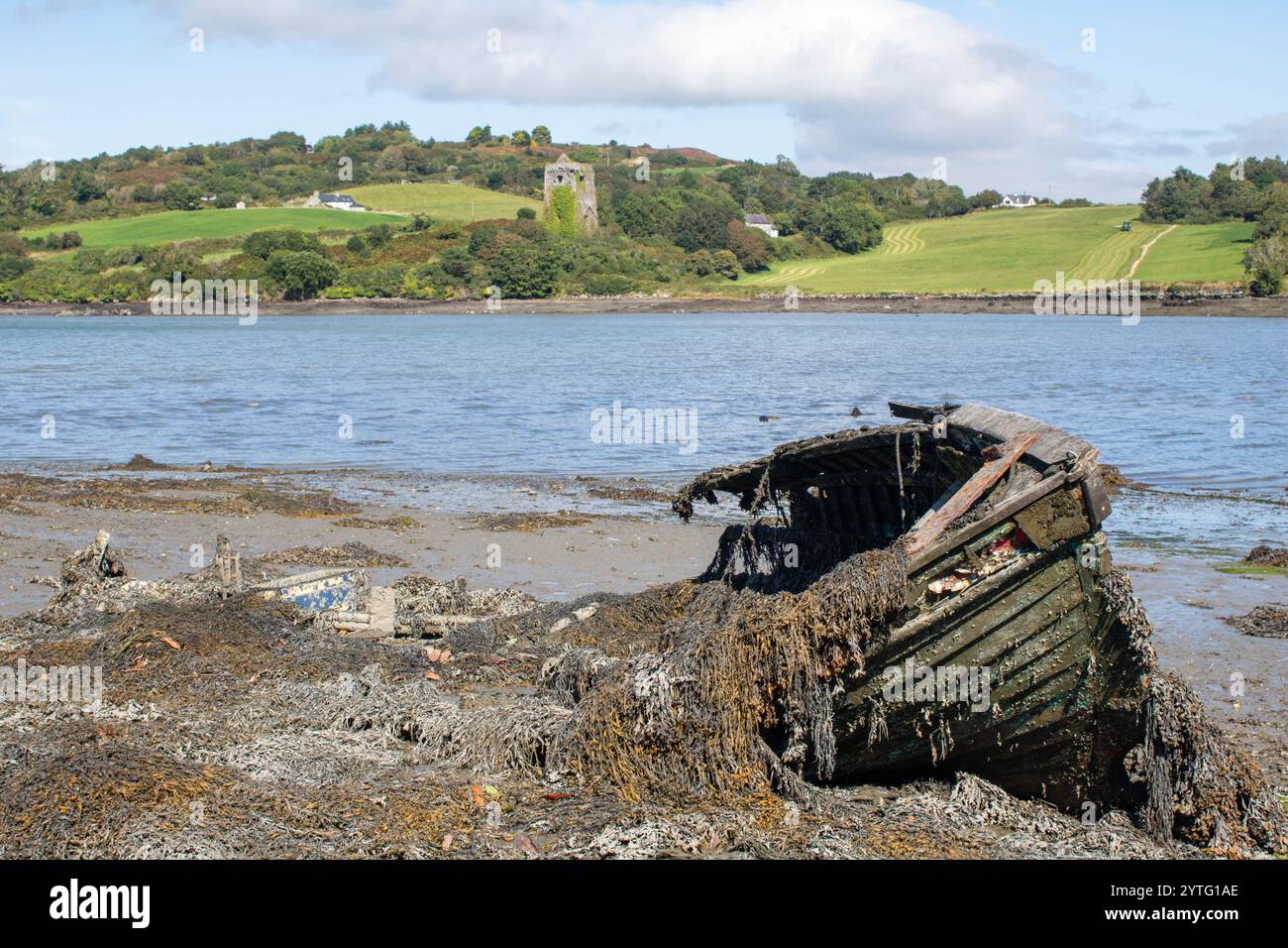Broken rowboat on the beach in west Cork covered with seaweed and sand ...