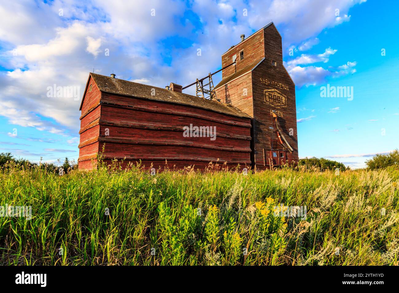 A red barn with a grain silo in the background. The barn is surrounded ...