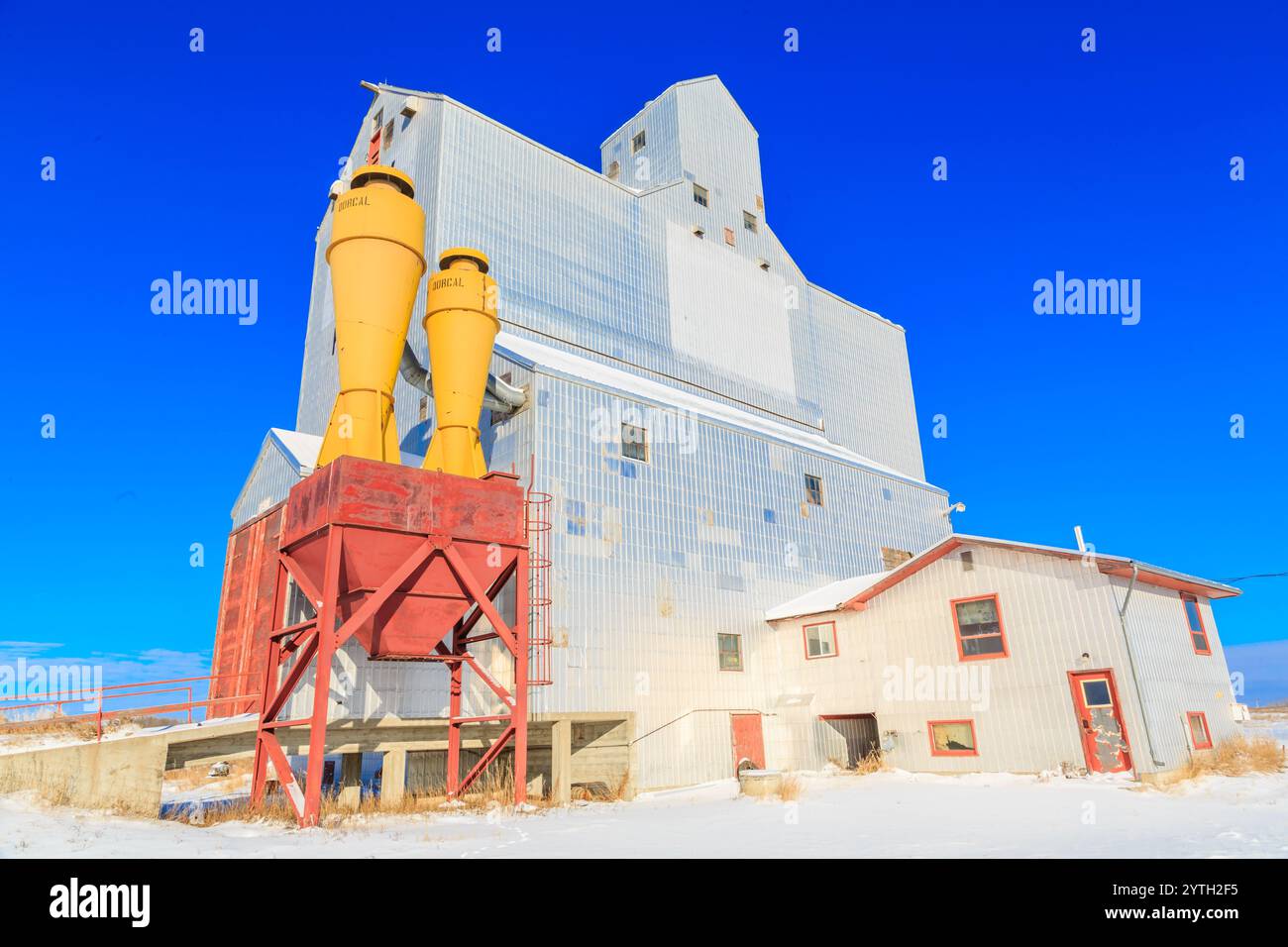 A large grain silo with two orange silos on top. The silos are empty ...