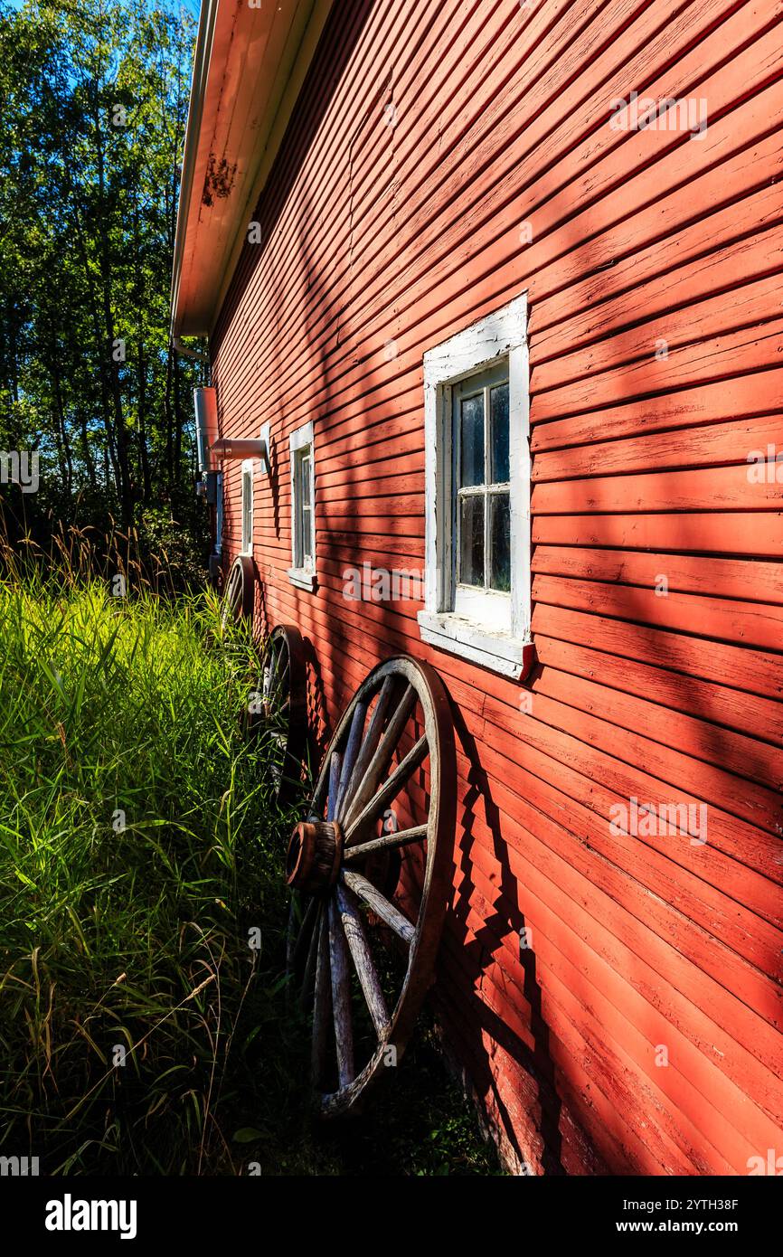 A red barn with a wheel on the side. The wheel is old and rusty. The ...