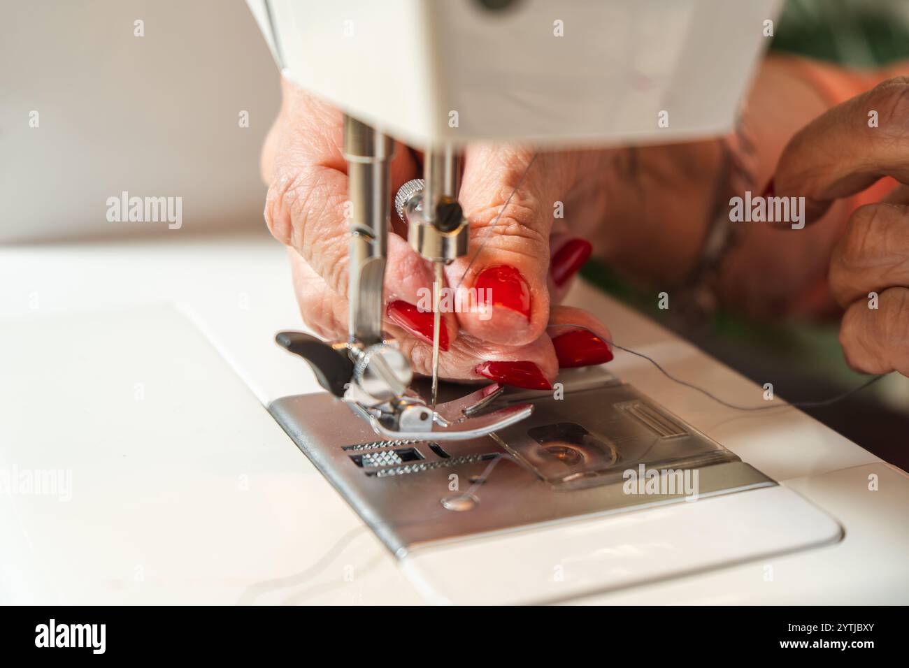 Seamstress threading the sewing machine needle before starting Stock ...
