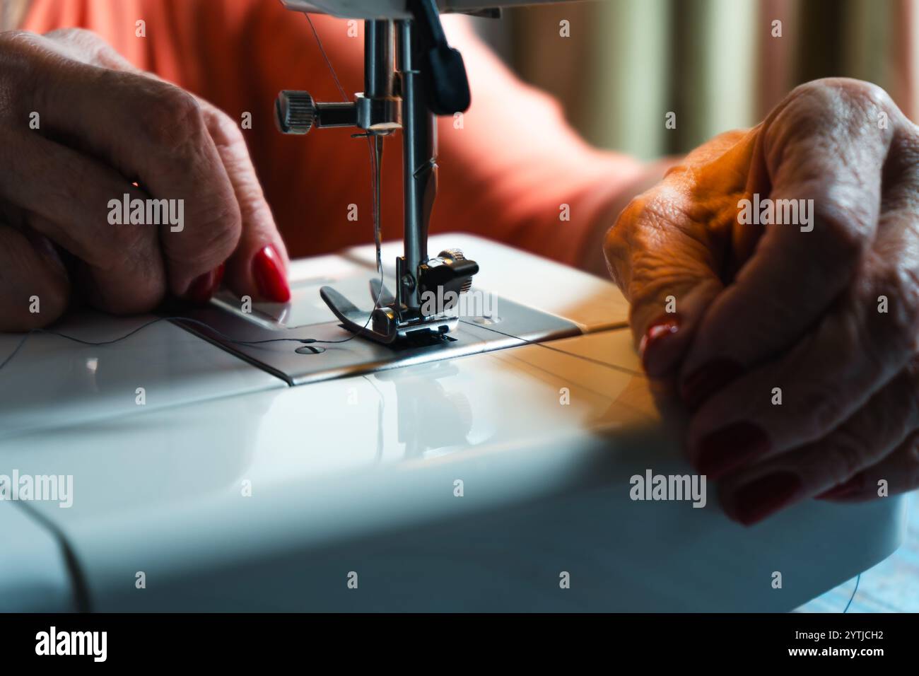 Seamstress threading the sewing machine needle before starting Stock ...
