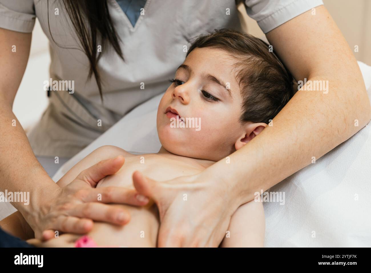 Physiotherapist performing respiratory physiotherapy on child's chest ...
