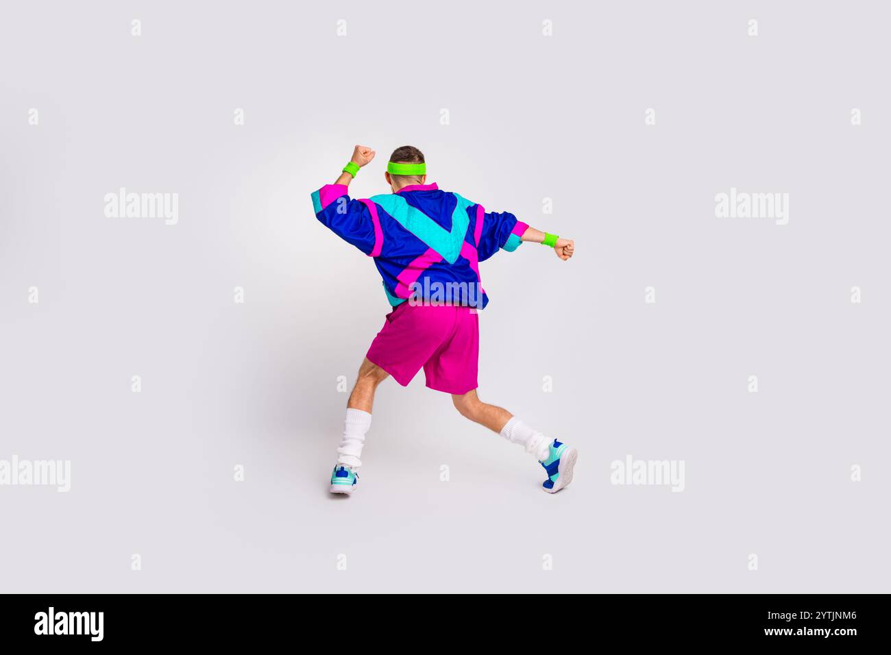 Energetic young man in vibrant retro activewear performing a dynamic ...