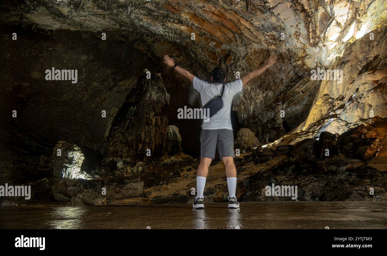 A visitor stands with arms raised, marveling at the impressive rock ...