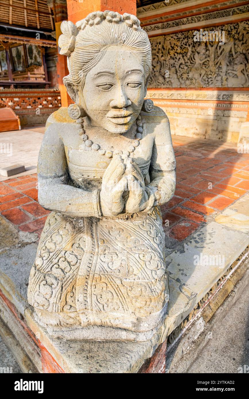 Traditional Balinese stone statue of a woman kneeling in prayer ...