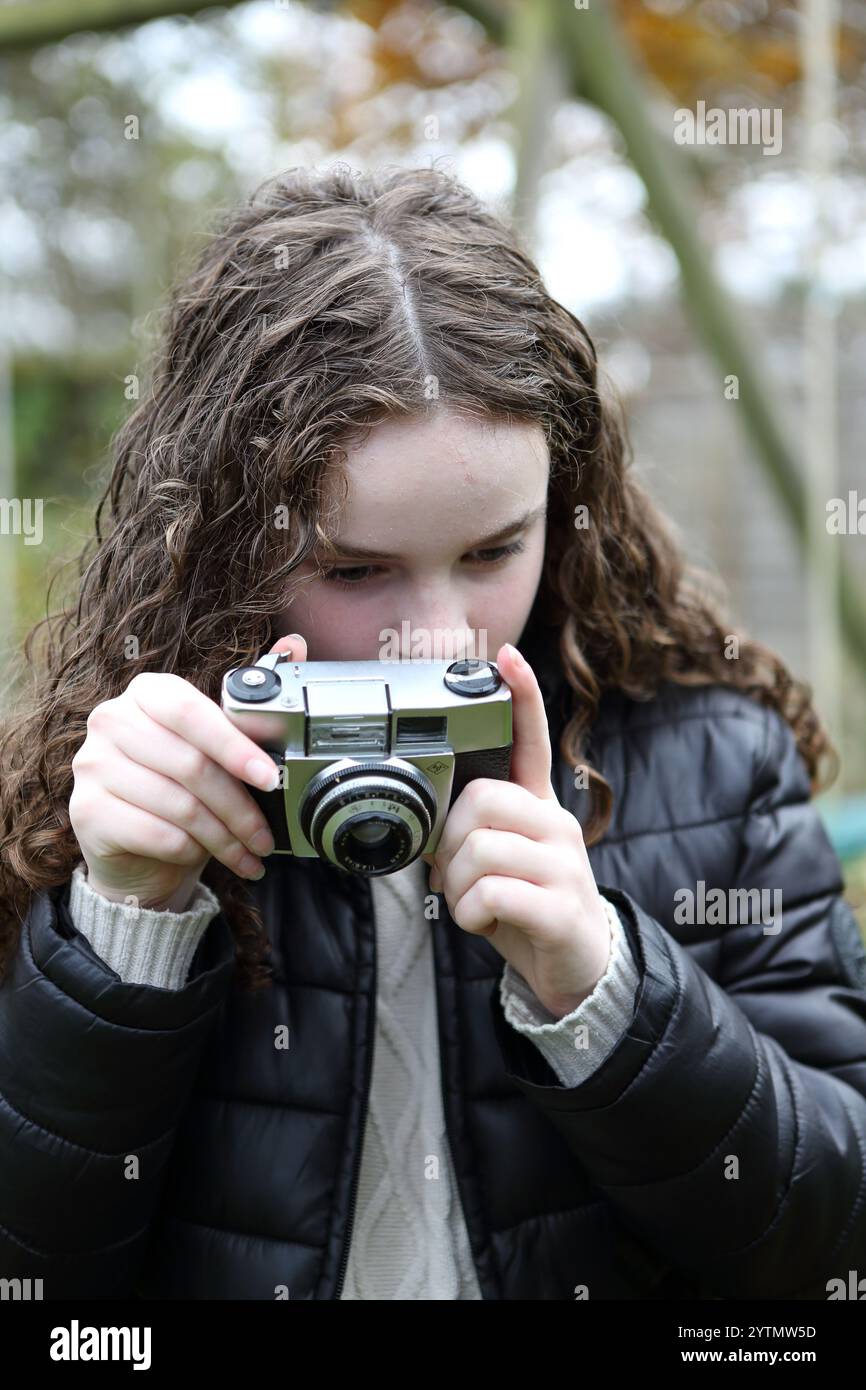 Teenage girl using a 35mm film camera analogue retro camera in garden ...