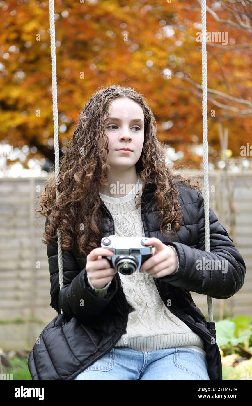 Teenage girl using a 35mm film camera analogue retro camera in garden ...