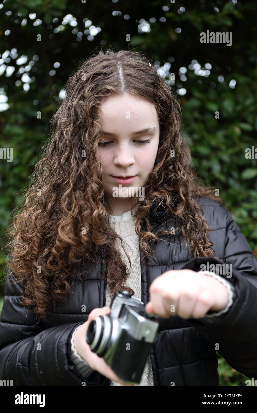 Teenage girl using a 35mm film camera analogue retro camera in garden ...