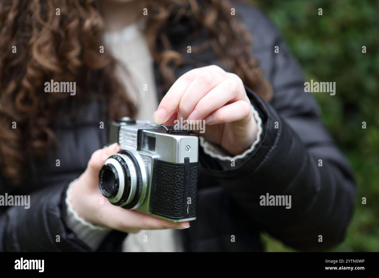 Teenage girl using a 35mm film camera analogue retro camera in garden ...