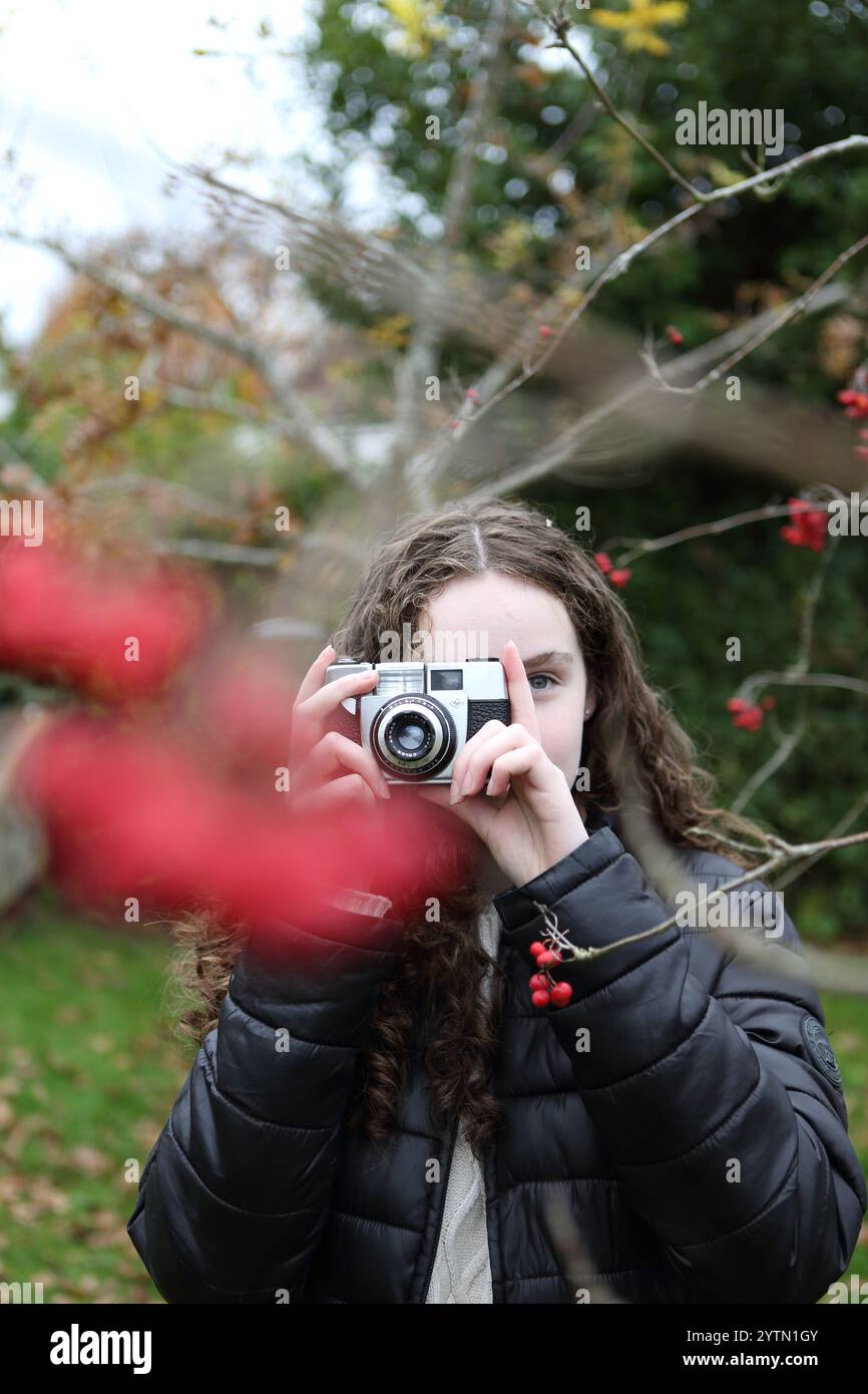 Teenage girl using a 35mm film camera analogue retro camera in garden ...