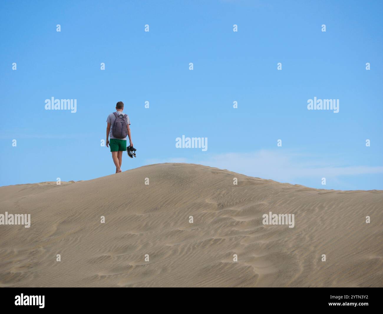 A man traveler tourist with a backpack walks through the desert holding ...