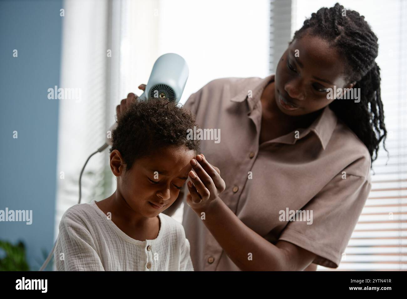 Young Black woman taking care of little son drying kids hair after ...
