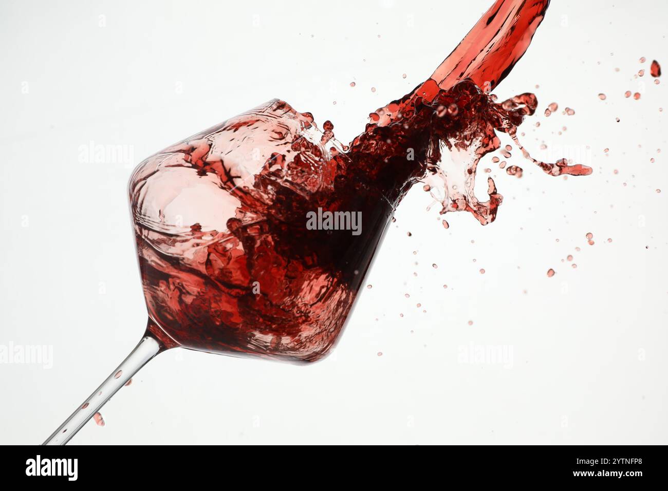 Pouring red wine into glass on white background Stock Photo - Alamy
