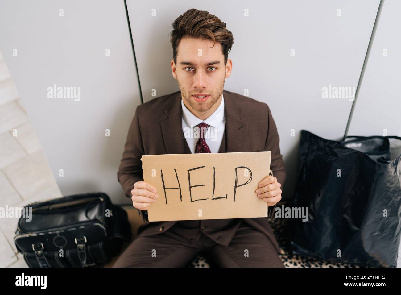 High-angle view of homeless businessman wearing suit and tie sitting on ...