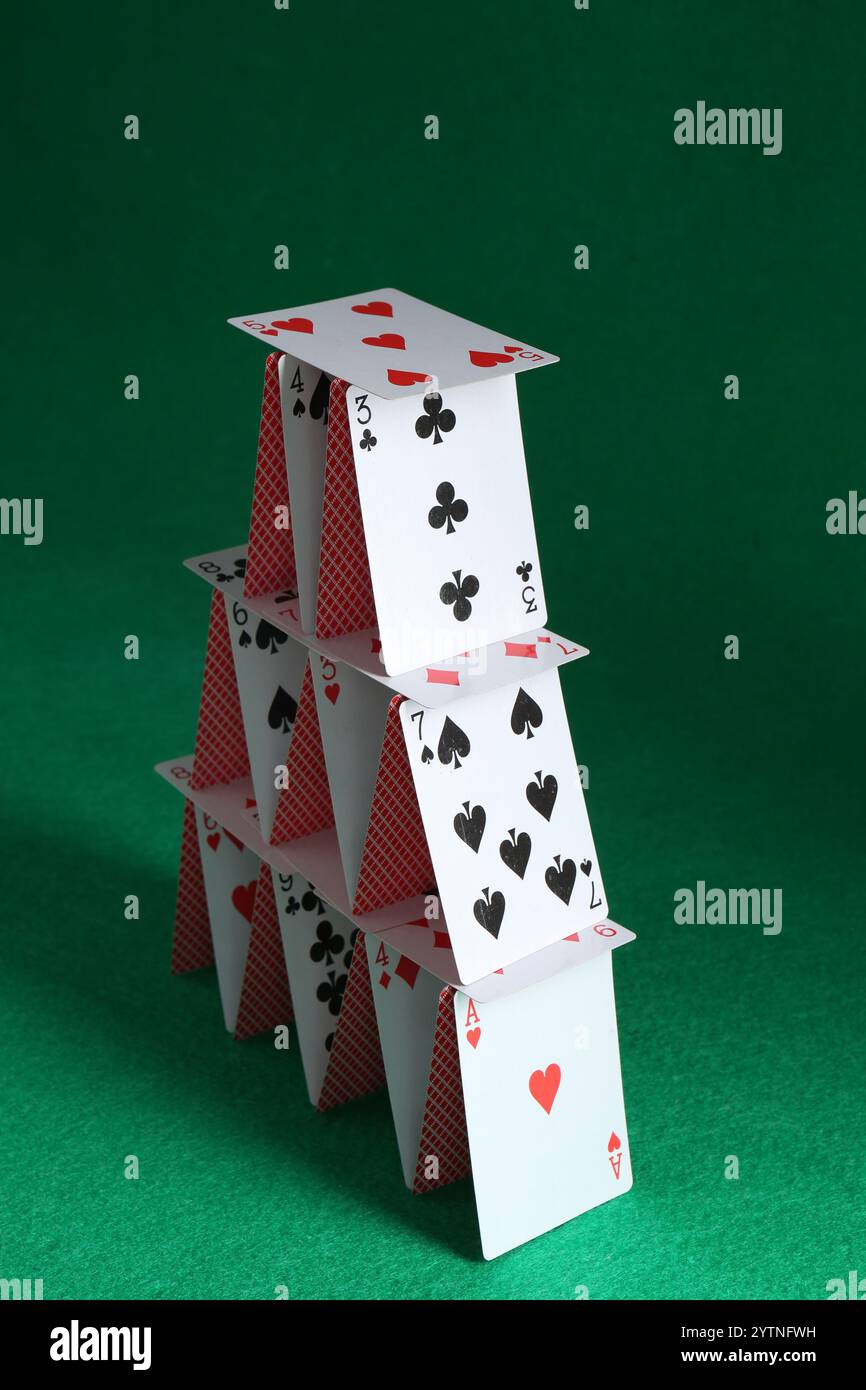 House of playing cards on green background Stock Photo - Alamy