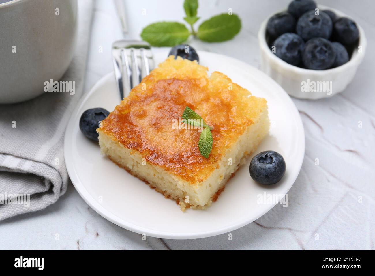 Slice of tasty semolina cake served on white textured table, closeup ...