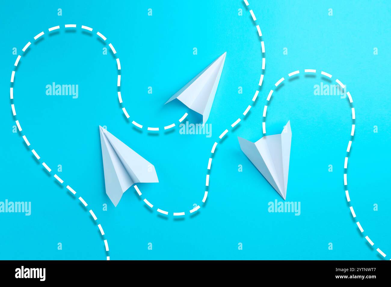 White paper planes with flight paths on light blue background. Dashed ...