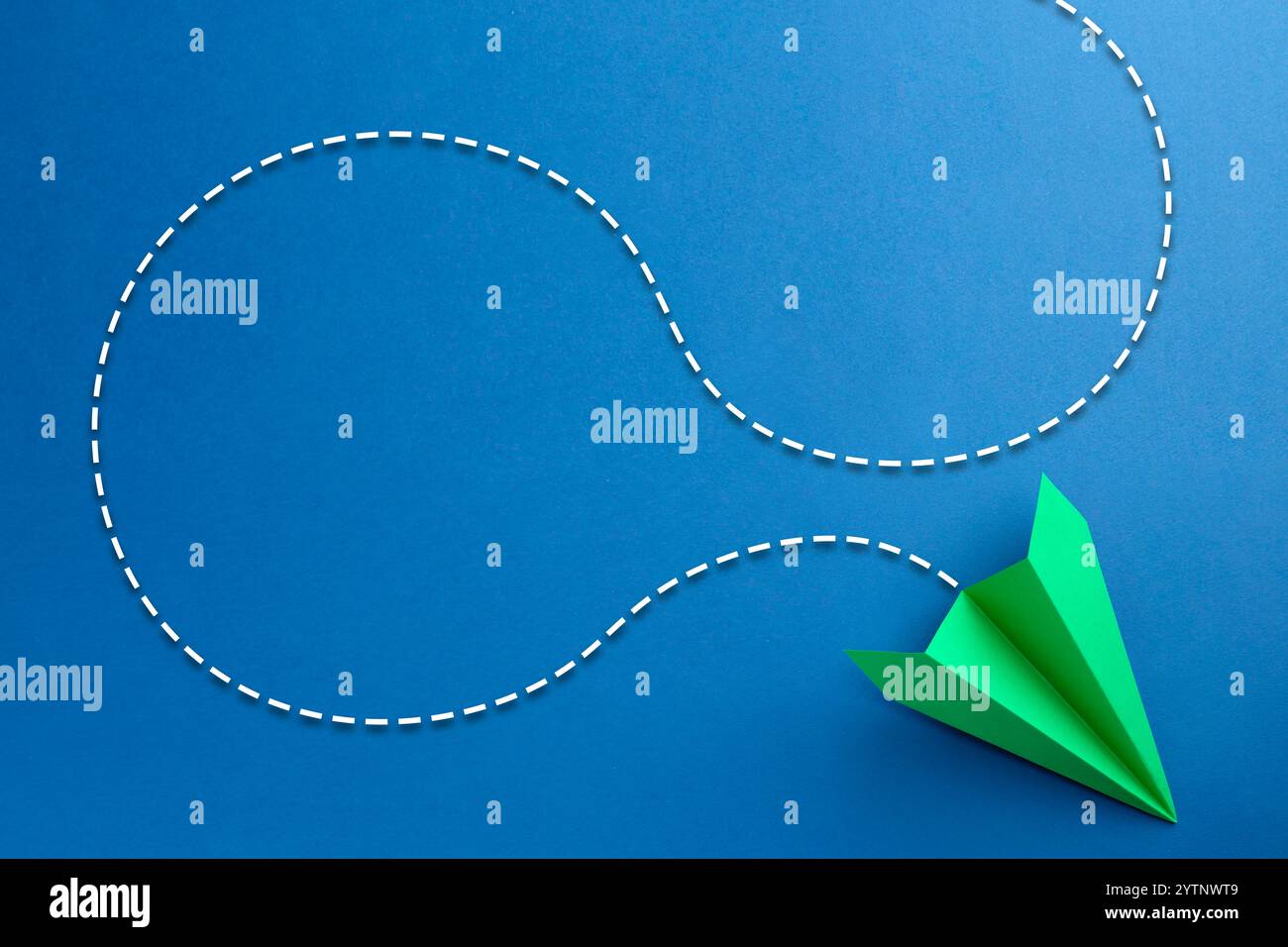 Green paper plane with flight path on blue background. Dashed line for ...