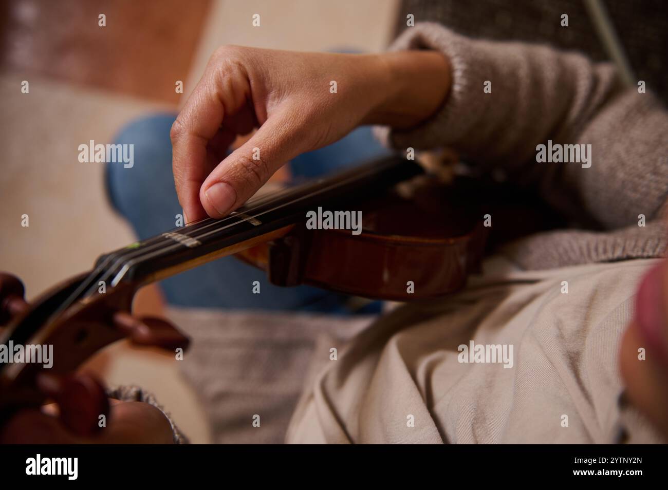 A detailed view of fingers gently playing a violin, capturing the ...