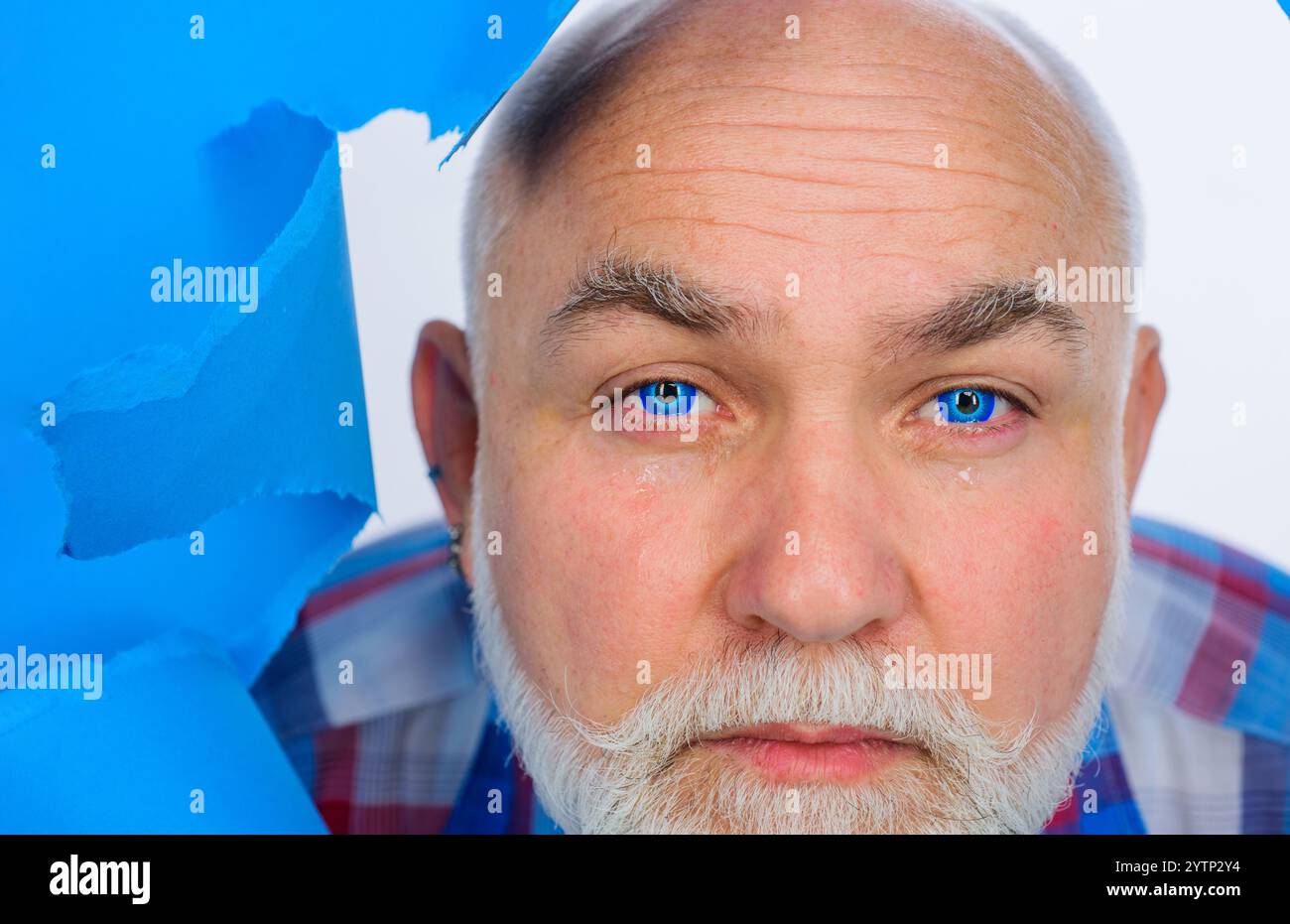 Closeup male face with blue color lenses in eyes looking through paper ...
