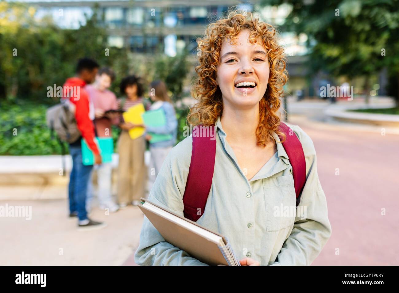 Smiling portrait of ginger student holding a binder on university ...