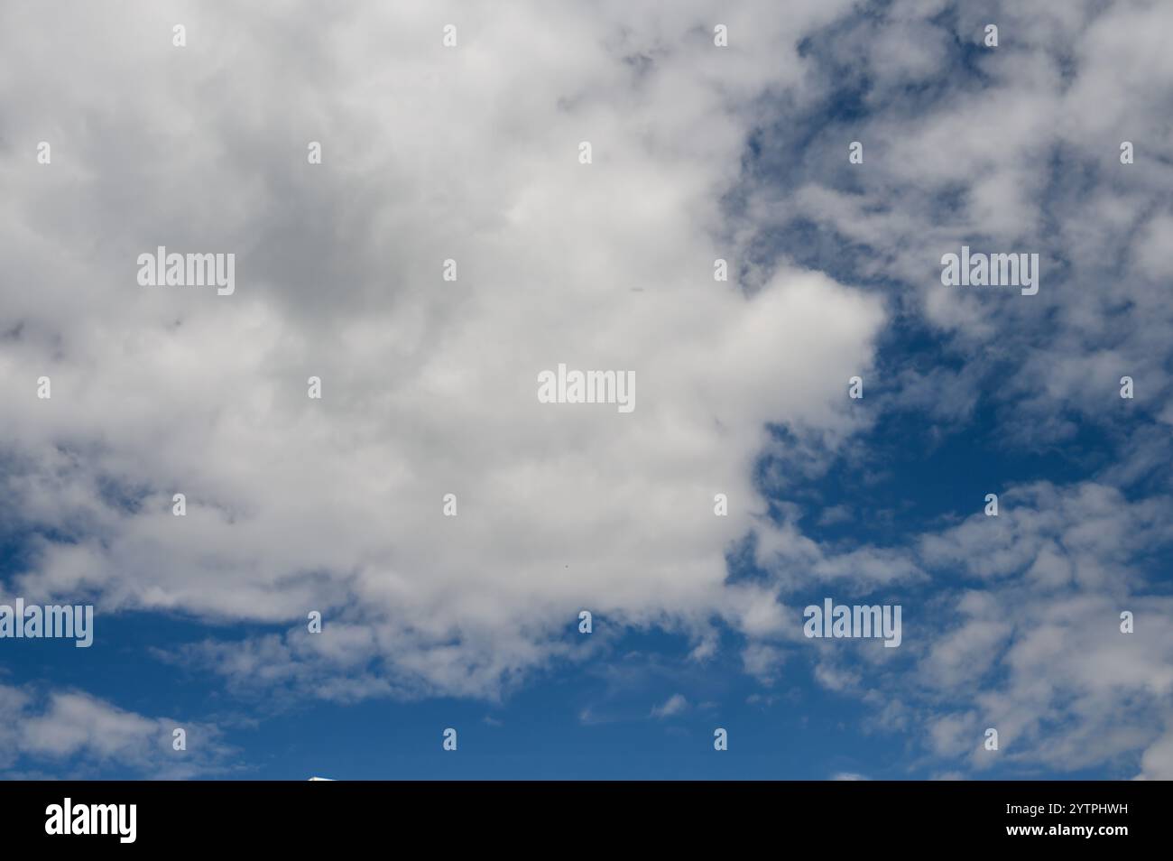 Fluffy white clouds float lazily in a clear blue sky, creating a ...