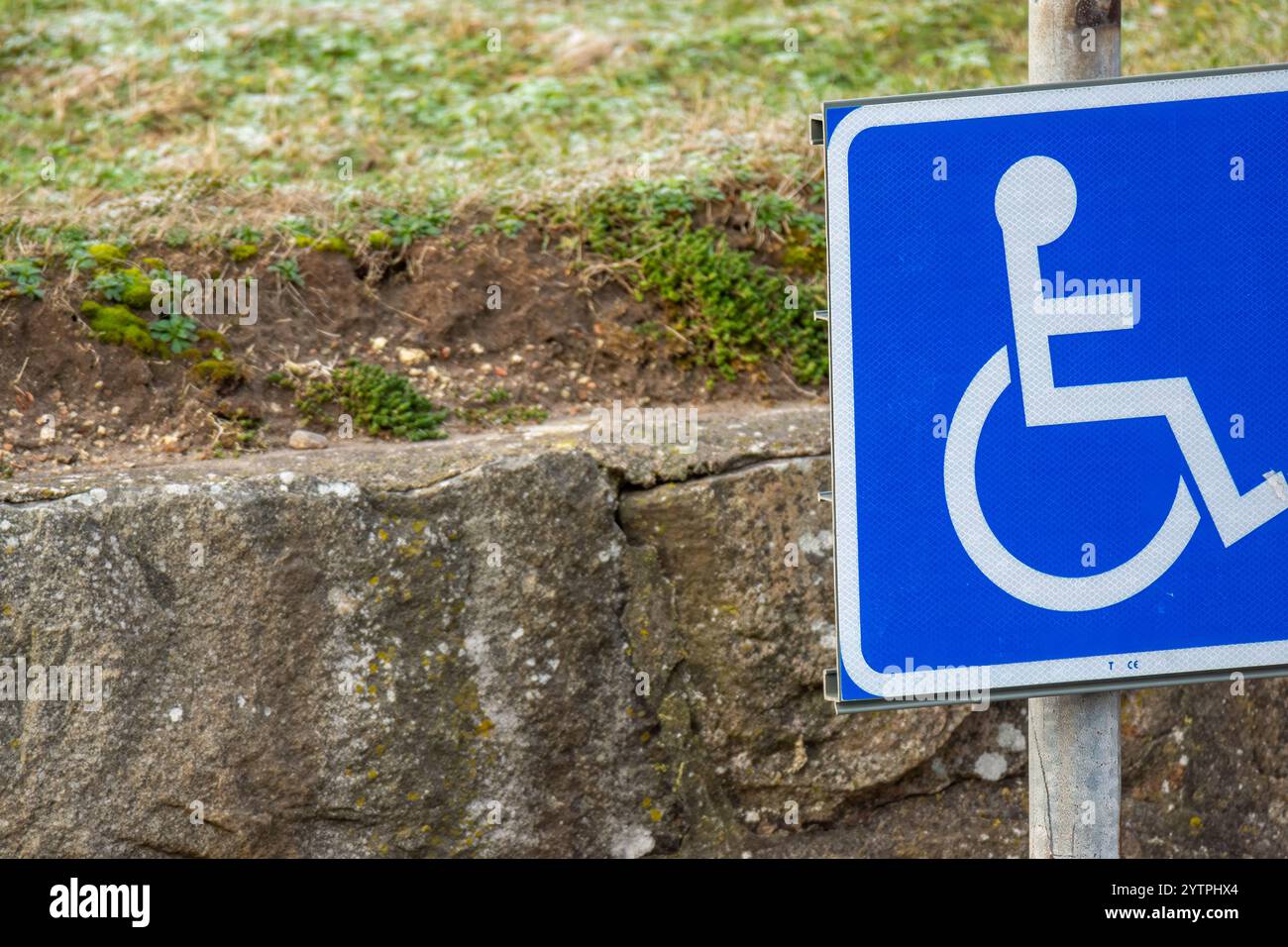 A blue accessibility sign with a wheelchair symbol is set against a ...