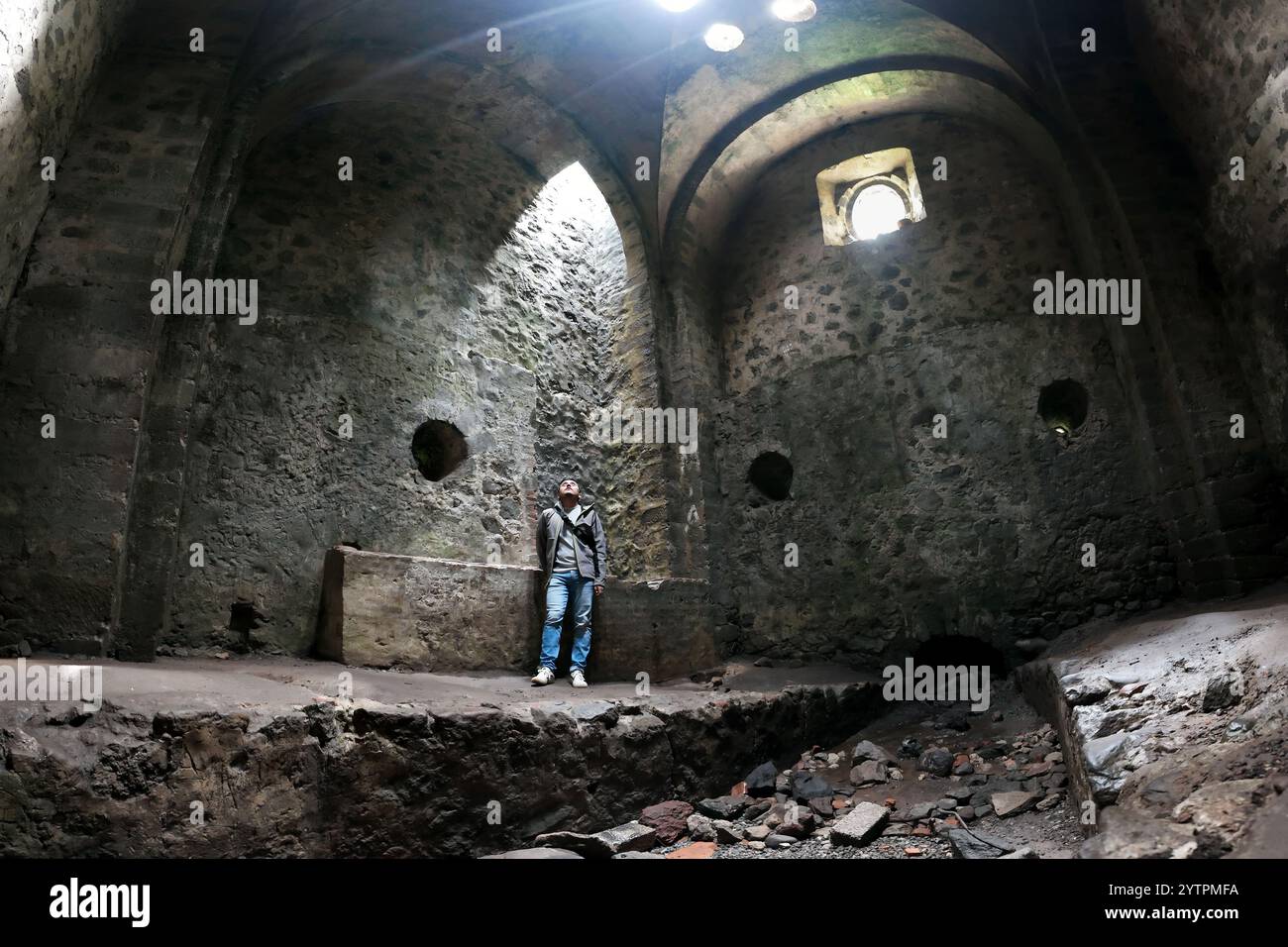 A person stands quietly inside an ancient stone structure, surrounded ...