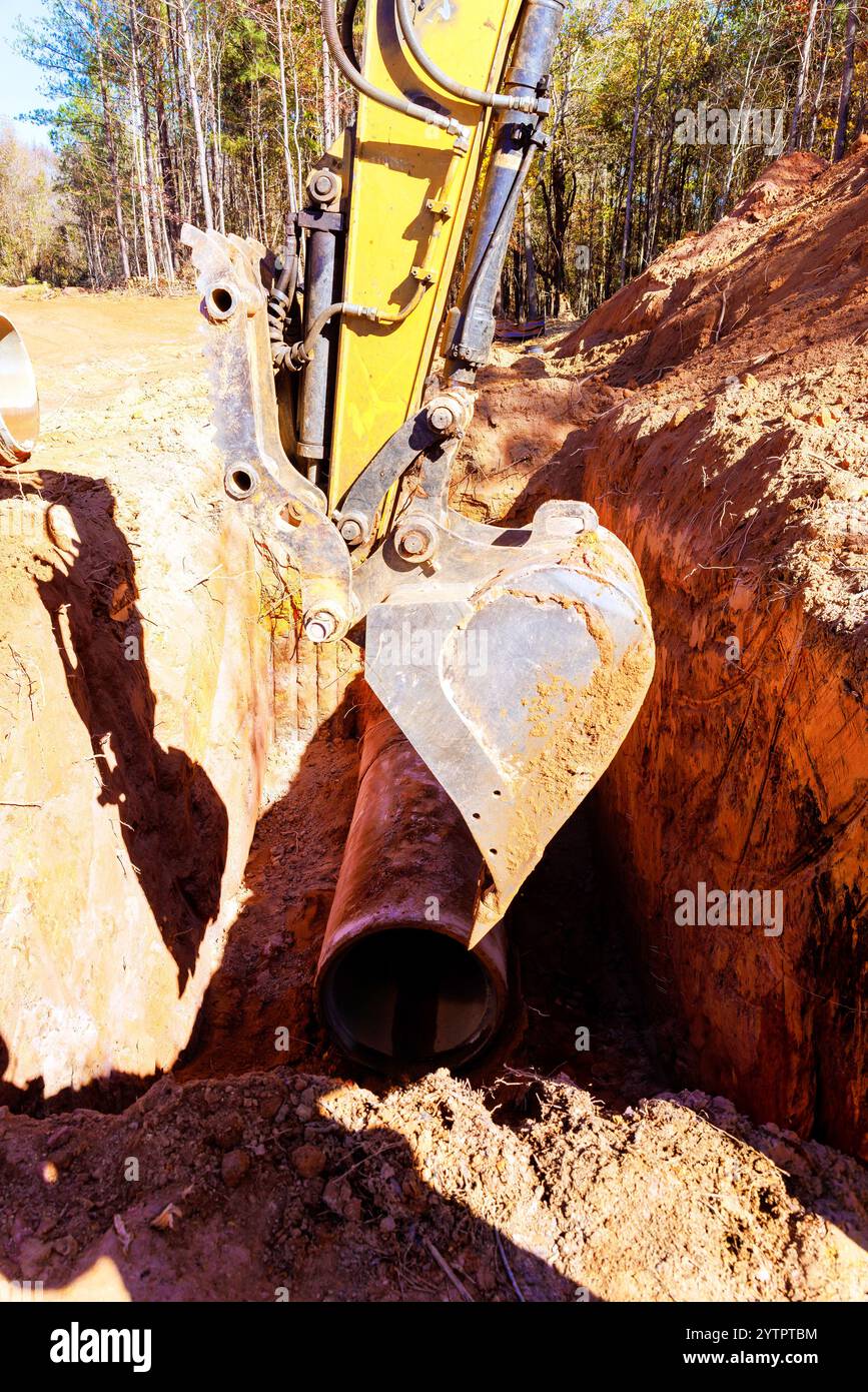 An excavator digs into earth to lay pipeline amidst to laying concrete ...