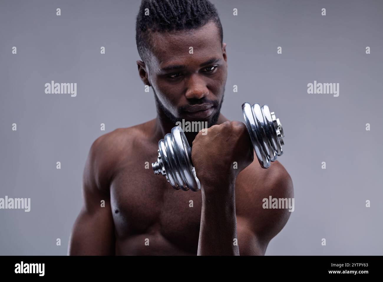Muscular black man lifts a dumbbell with a determined expression ...