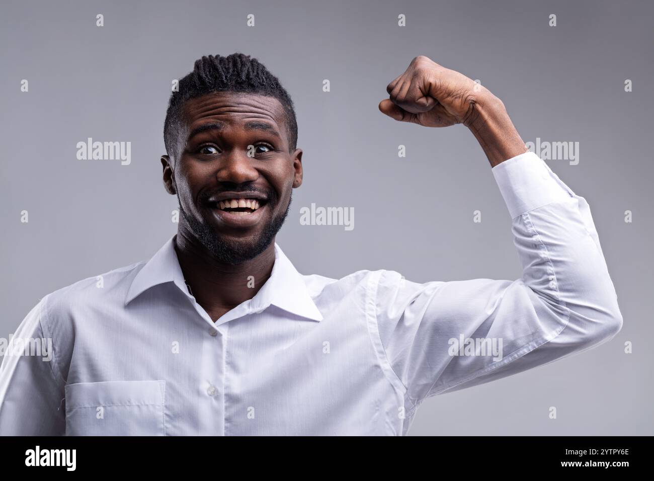 Excited young adult businessman flexing his bicep and smiling at the ...