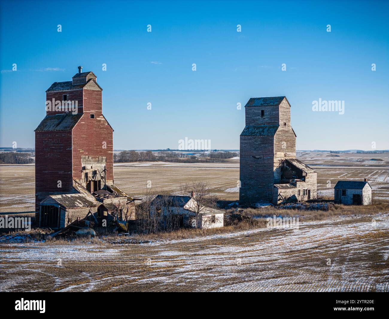Two old grain silos are in a field with a snowy landscape. The silos ...