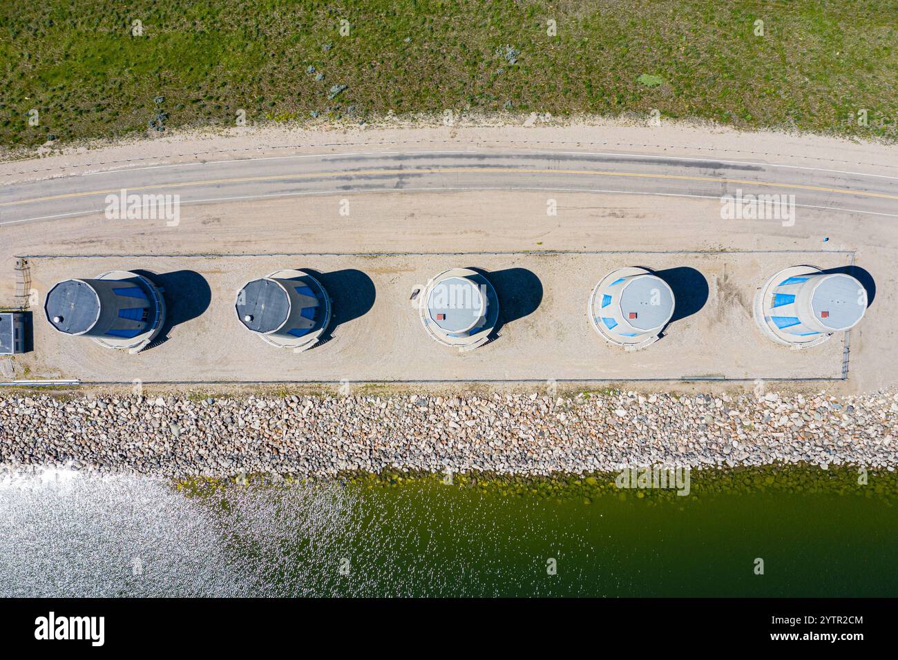 A series of four tanks are lined up on a beach. The tanks are all the ...