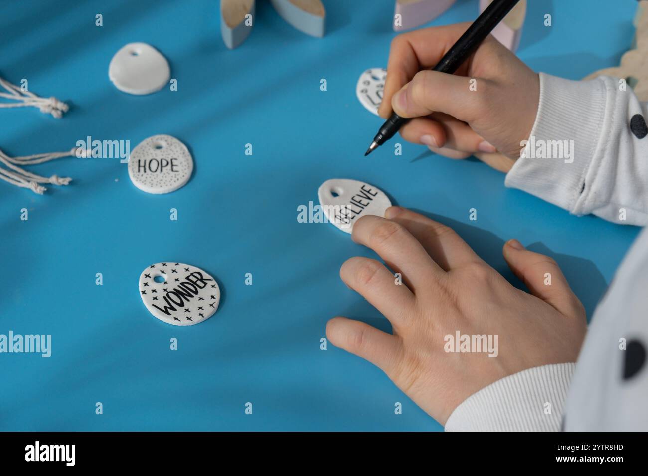 Workshop writing word BELIEVE on EASTER clay egg Creator is using white ...