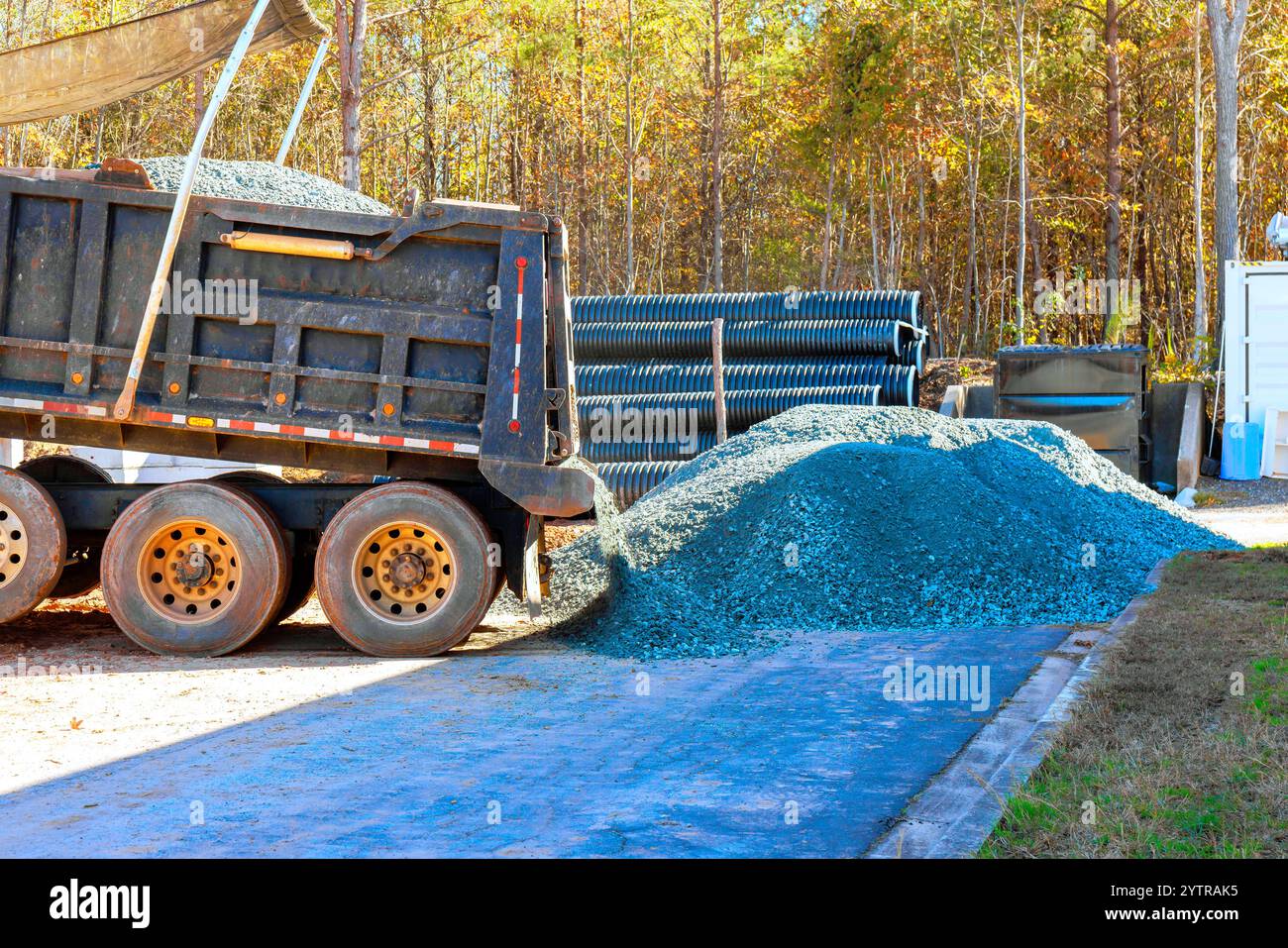 Dump truck releases large pile of gravel on gravel surface near ...