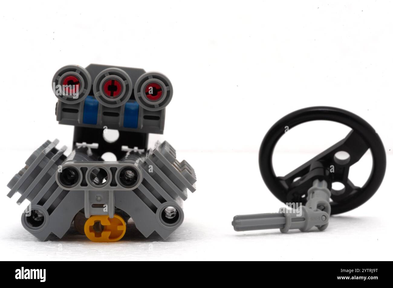A toy car engine with a steering wheel. The engine is on a white ...