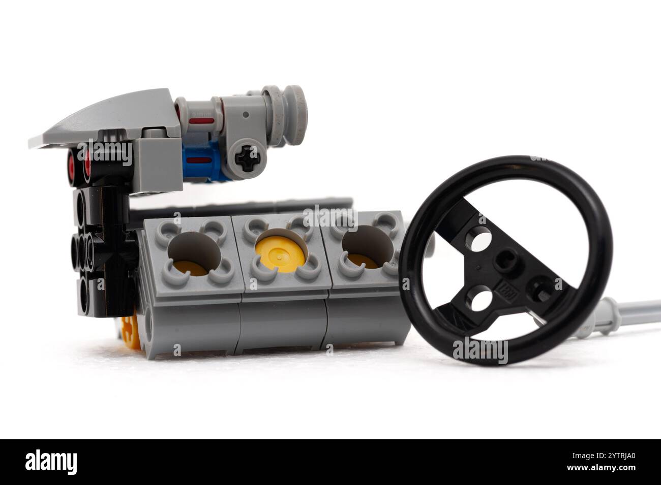 A toy car engine with a steering wheel. The engine is on a white ...