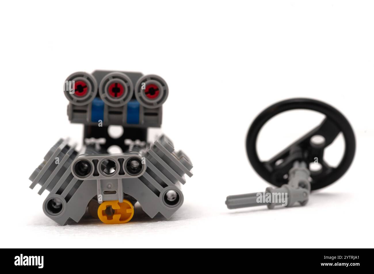 A toy car engine with a steering wheel. The engine is on a white ...