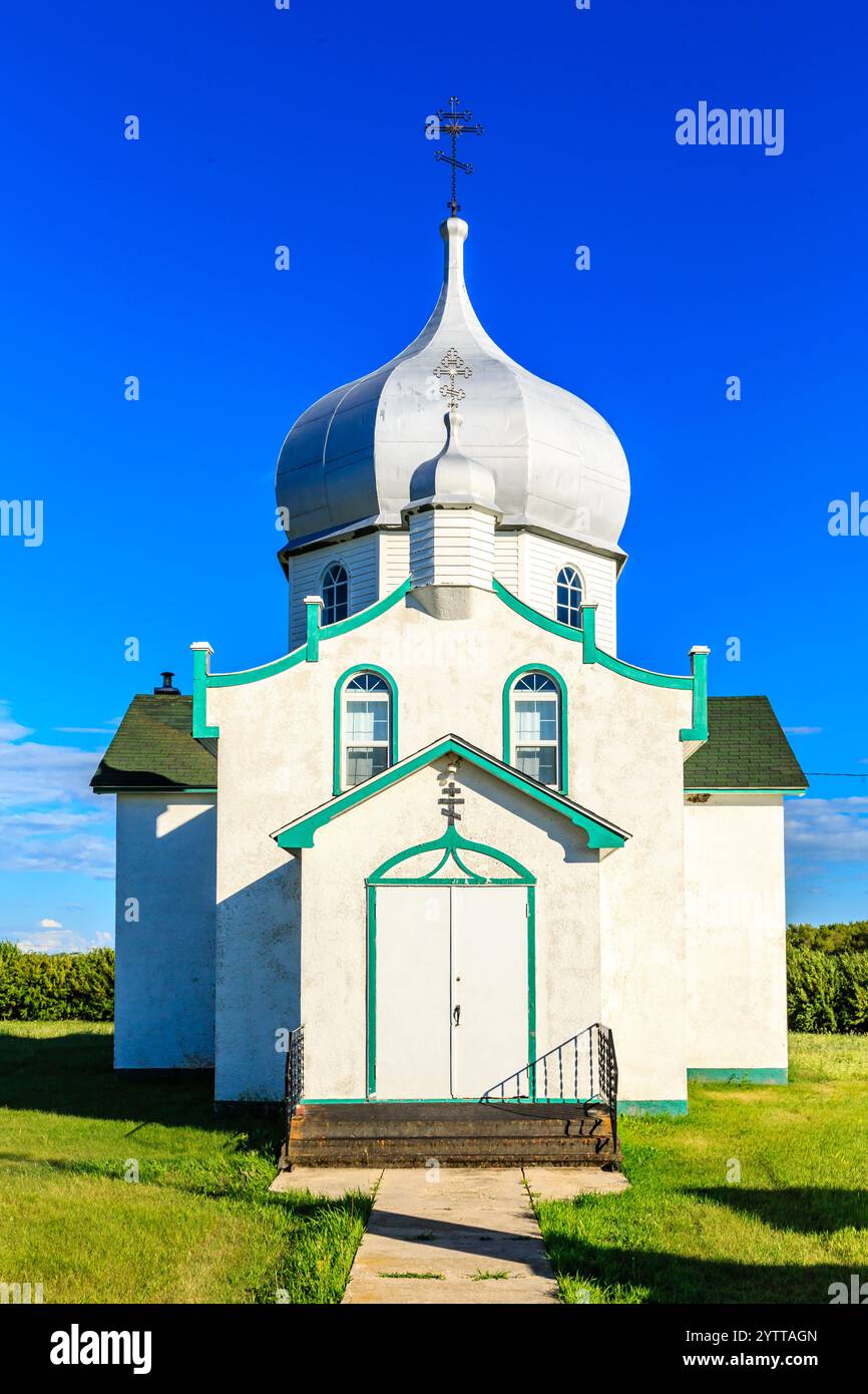 A small white church with a green roof and a cross on top. The building ...