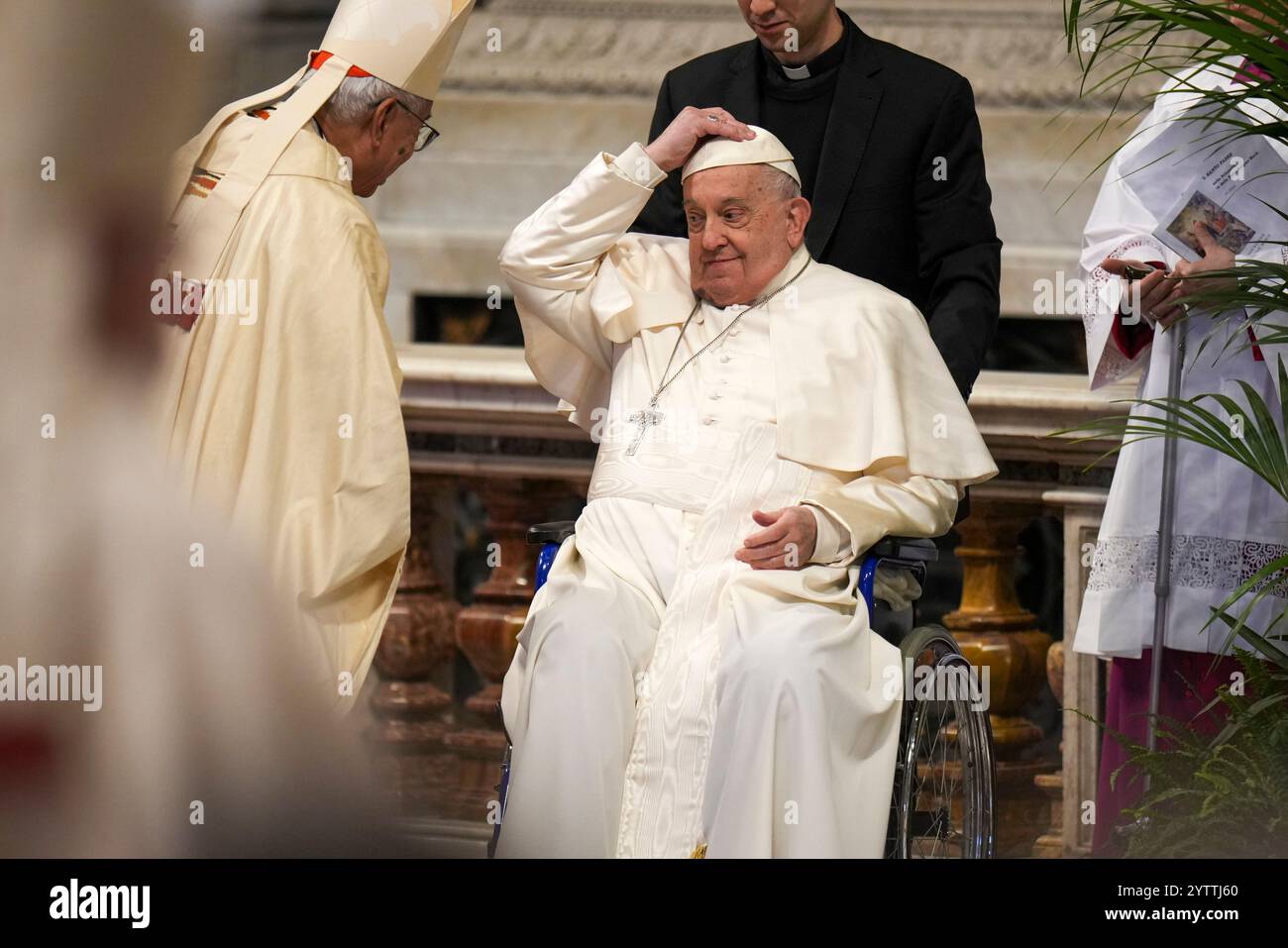 Pope Francis puts on a skull cap he received from a cardinal as he ...
