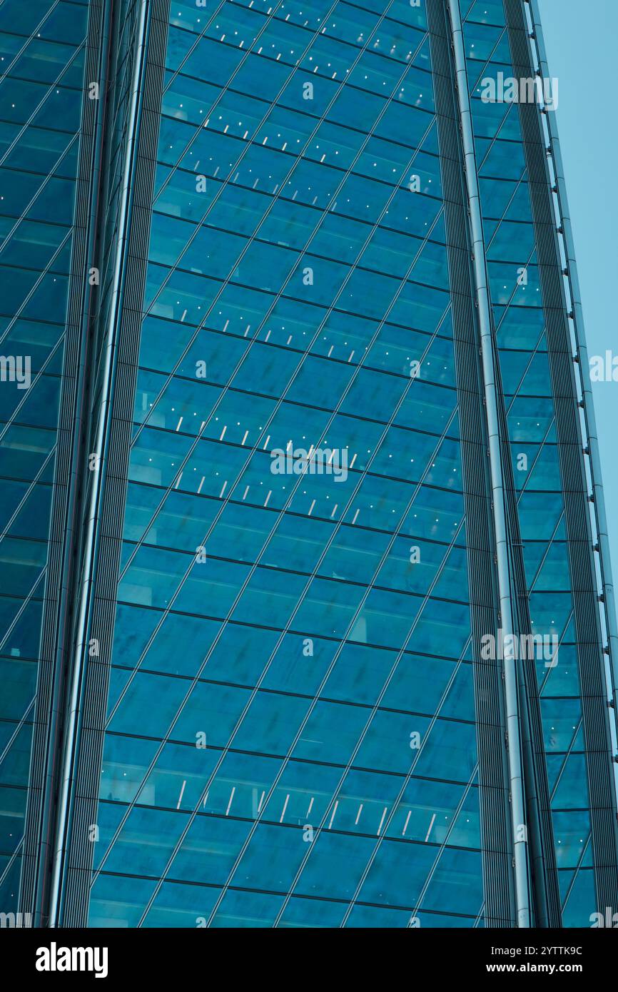 A modern glass building facade displays reflections and contemporary ...