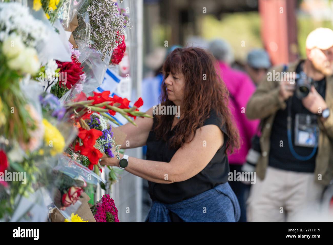A woman places flowers in the temporary fence at the burnt Adass Israel ...