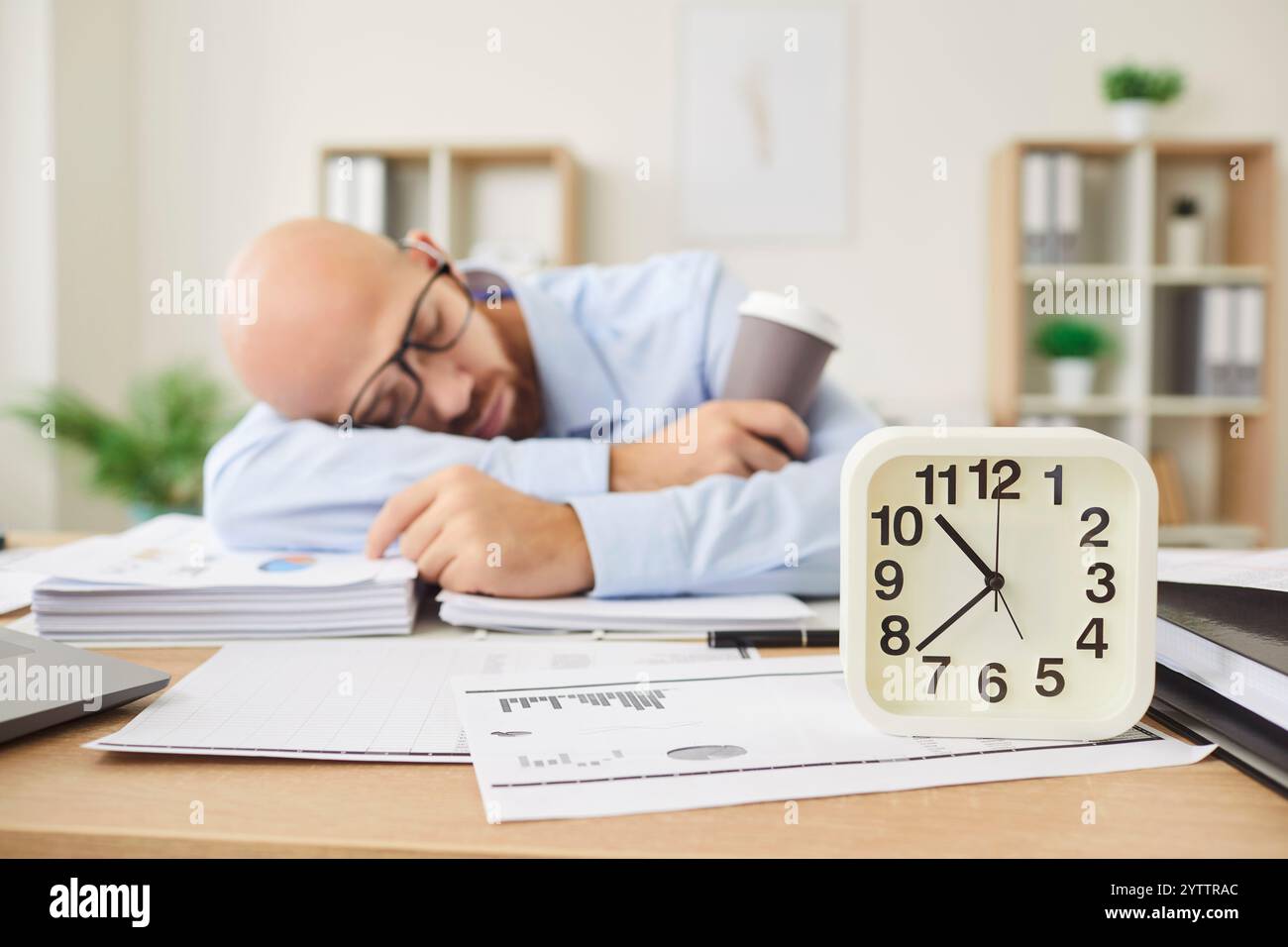 Overworked tired young business man sleeping on his workplace in office ...