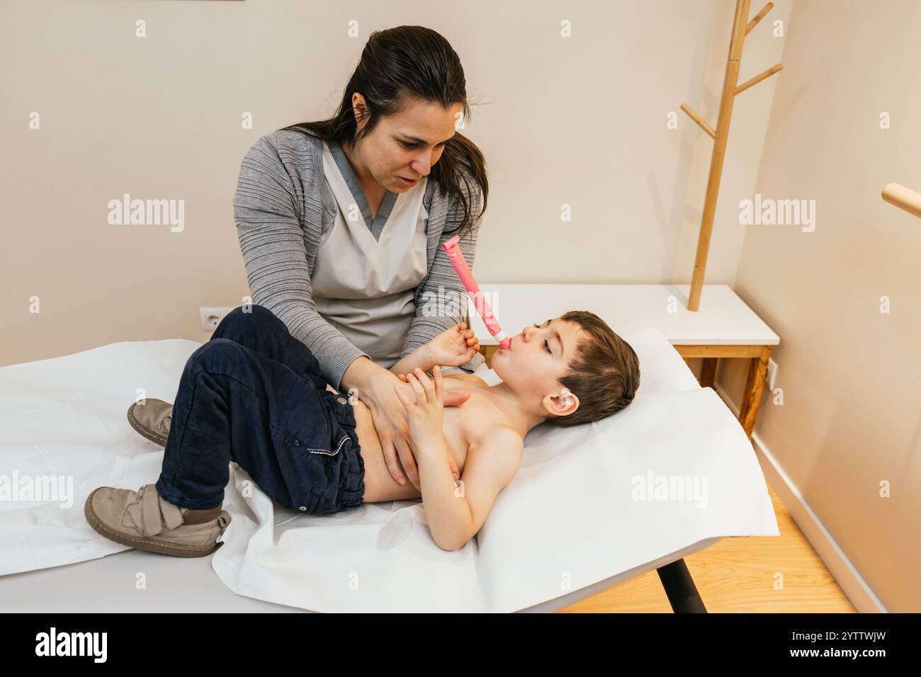 Physiotherapist assisting young boy with respiratory physiotherapy ...