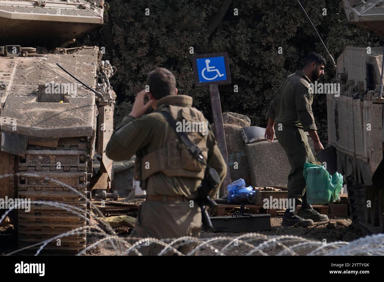 Israeli armored vehicles park next to a sign for the disabled near the ...
