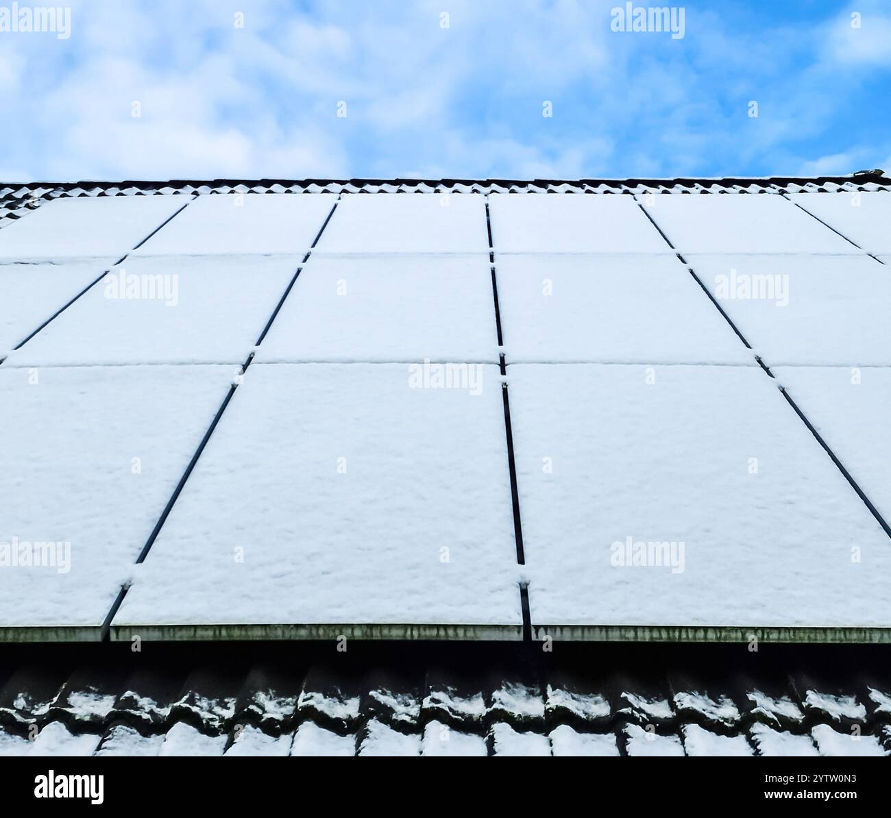 Snow covered solar panels producing clean energy on a roof of a house ...