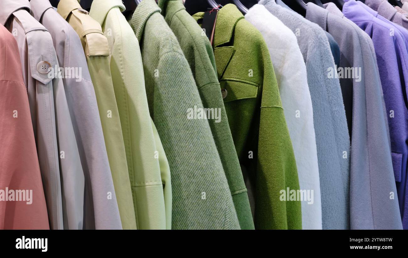 A row of clothes on a rack, with a green jacket in the middle. The ...