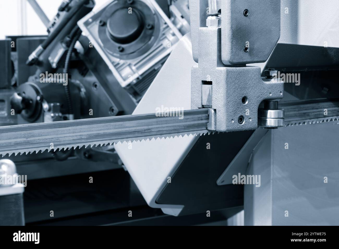 A machine with a blade cutting through a piece of metal. The blade is ...