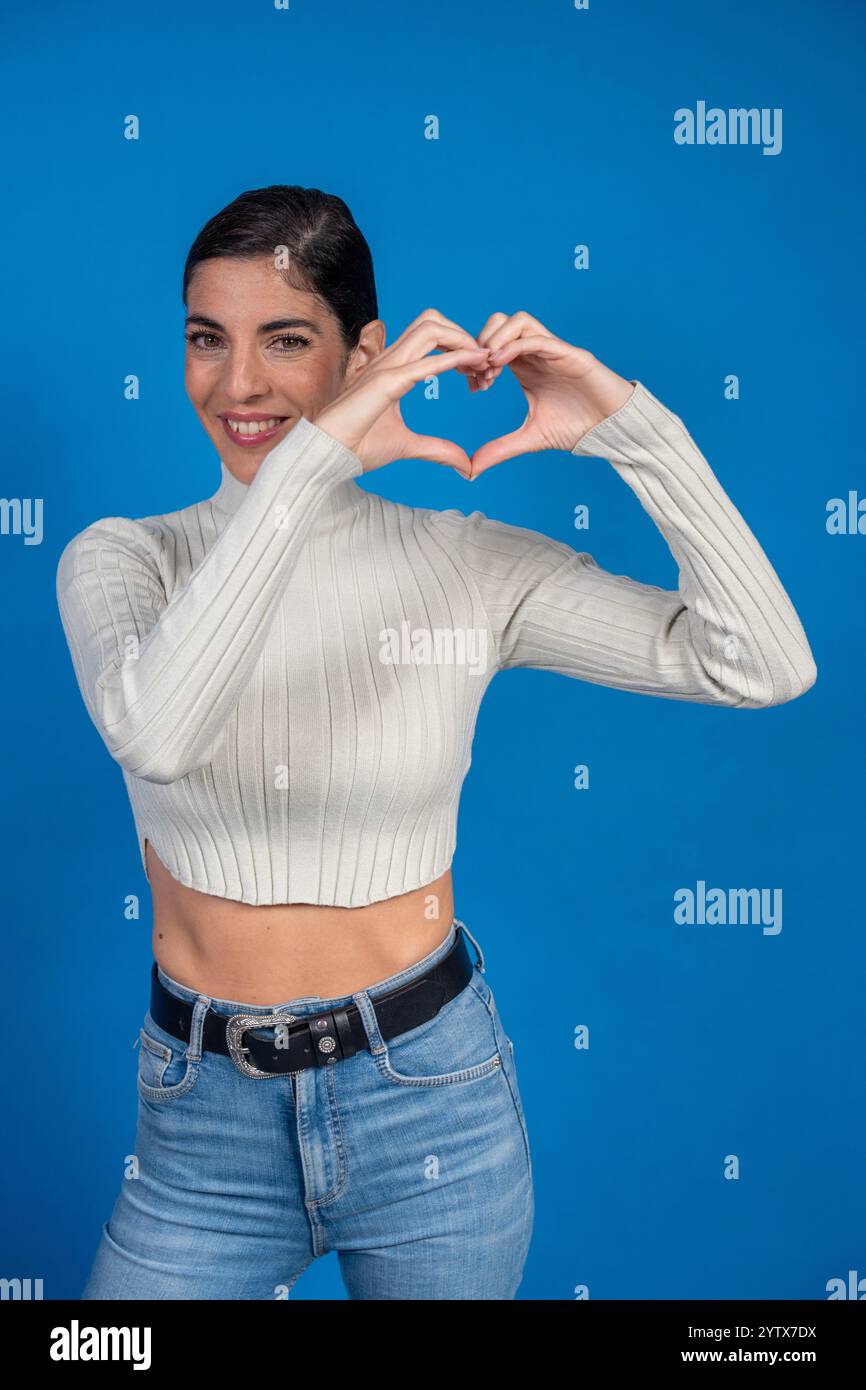 Young woman forming heart shape with hands, expressing love, care, and ...